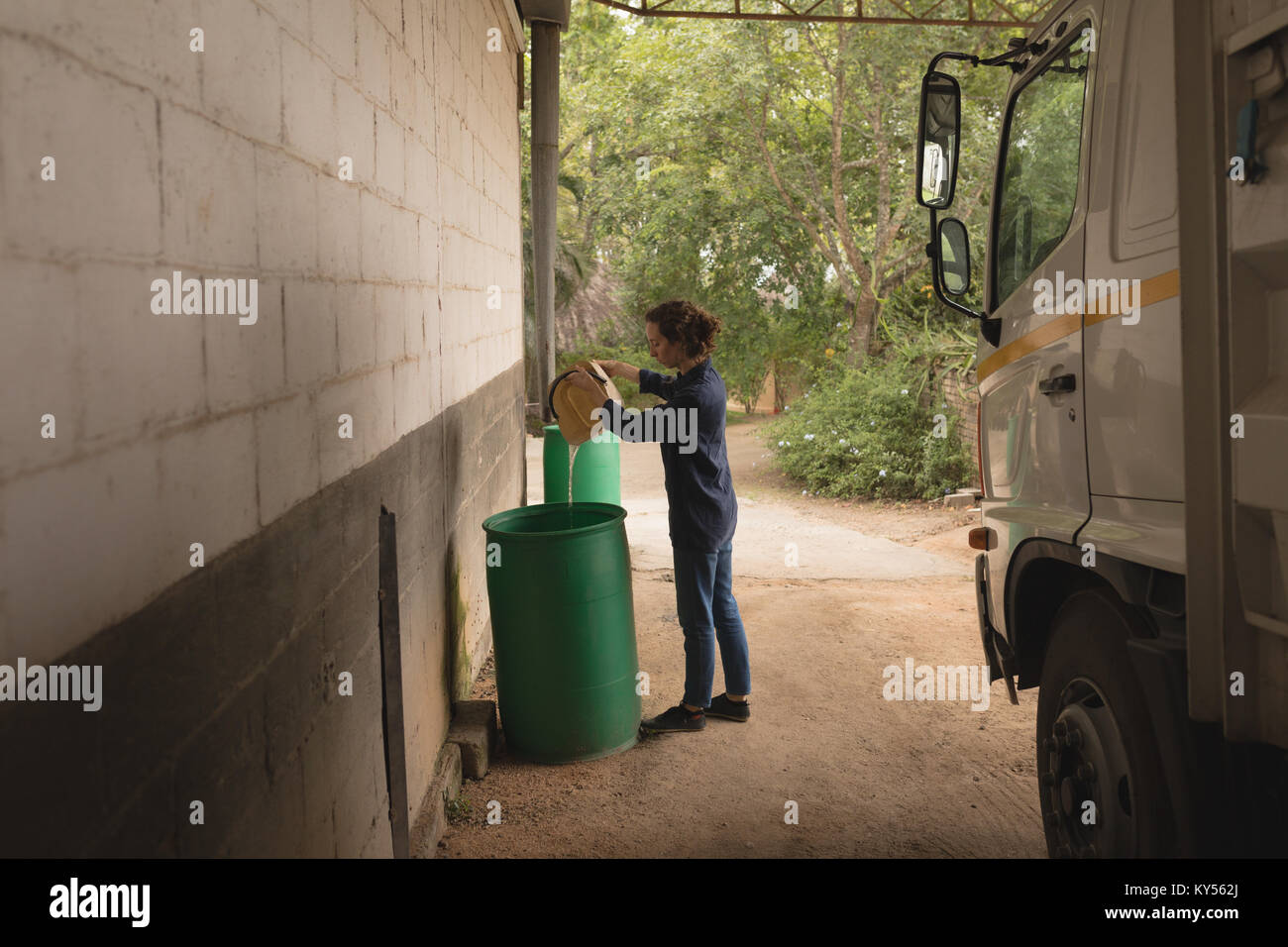 Woman pouring water into storage barrel Stock Photo - Alamy