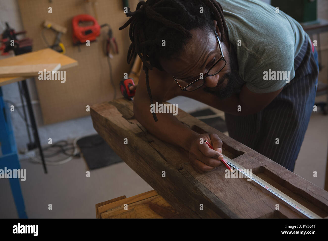 Carpenter measuring wooden plank with tape measure Stock Photo - Alamy