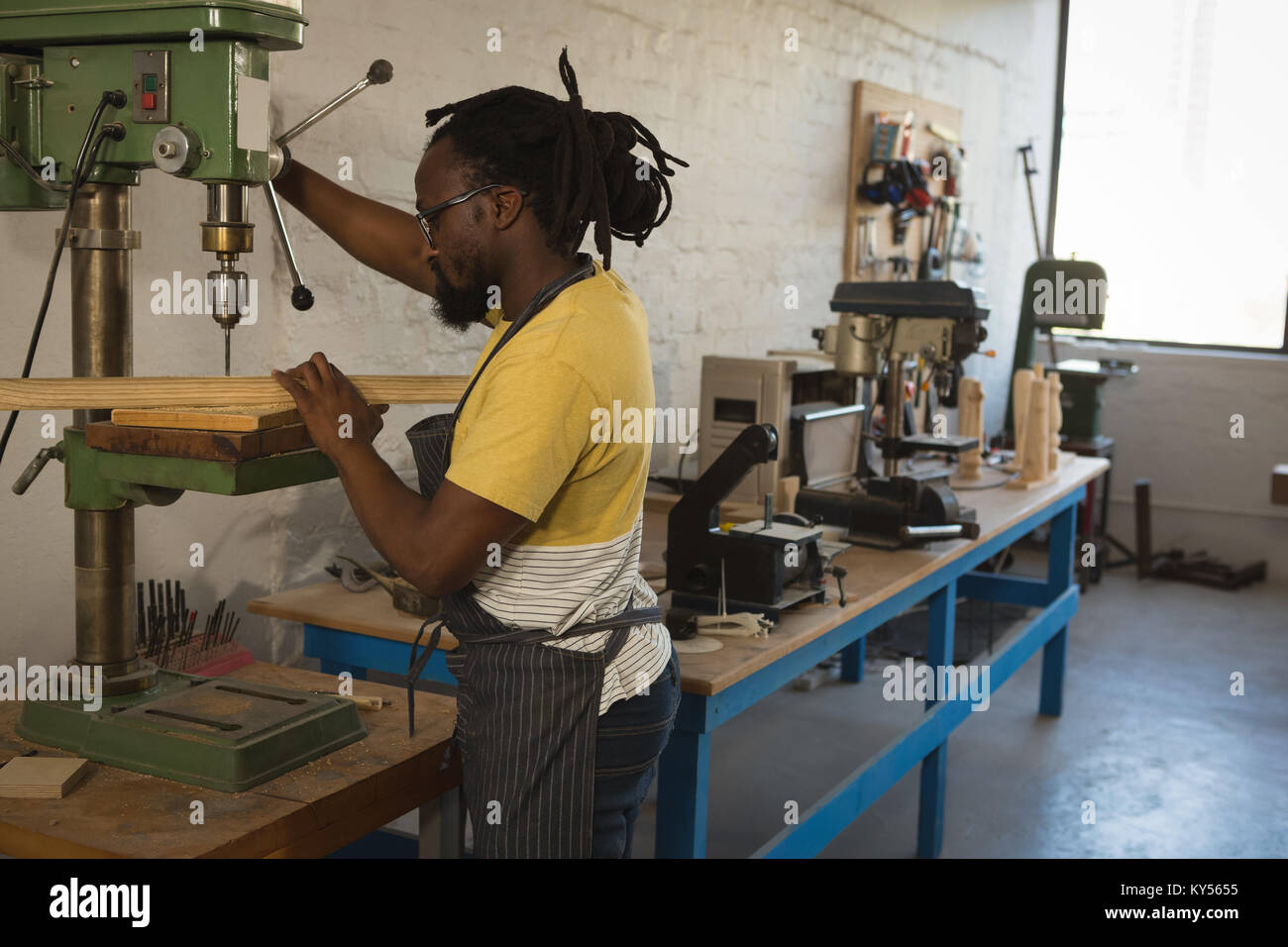 Carpenter drilling wooden plank with machine Stock Photo - Alamy