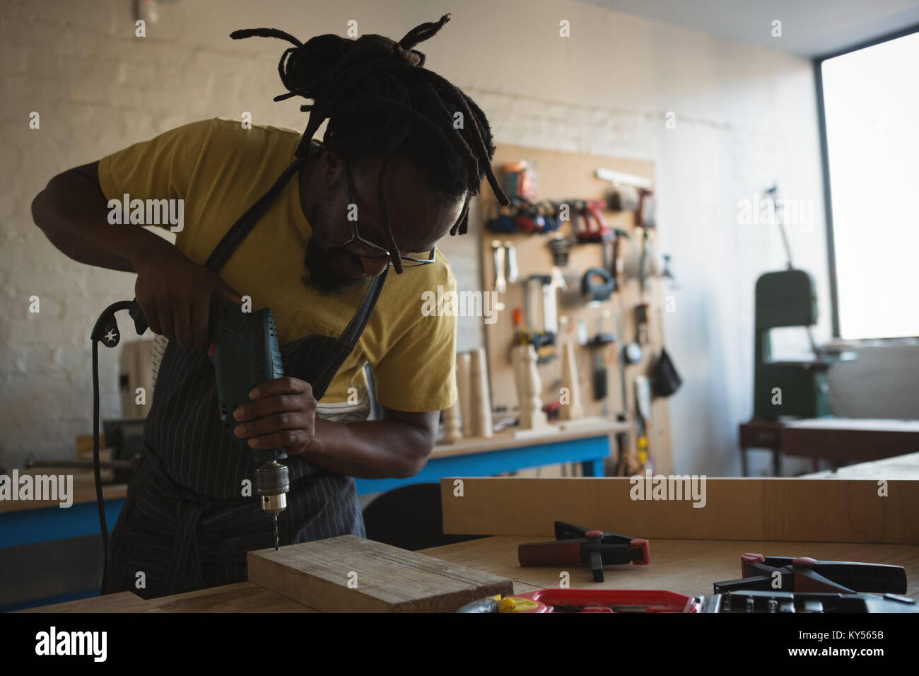Carpenter drilling wooden plank with machine Stock Photo - Alamy