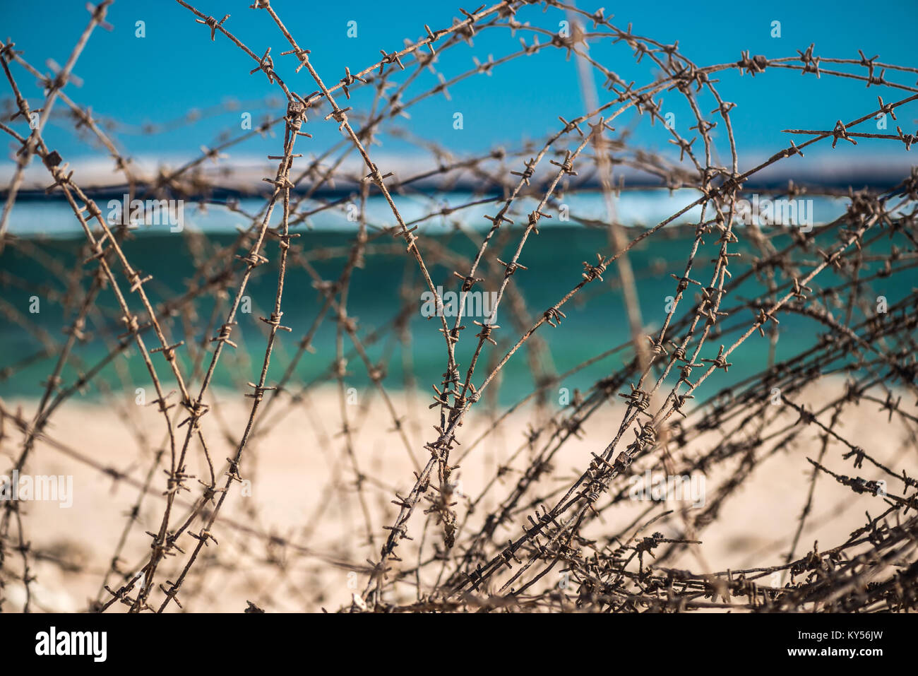 Old barbed wire infront of sea. Wire and blue sky with clouds. Safety ...