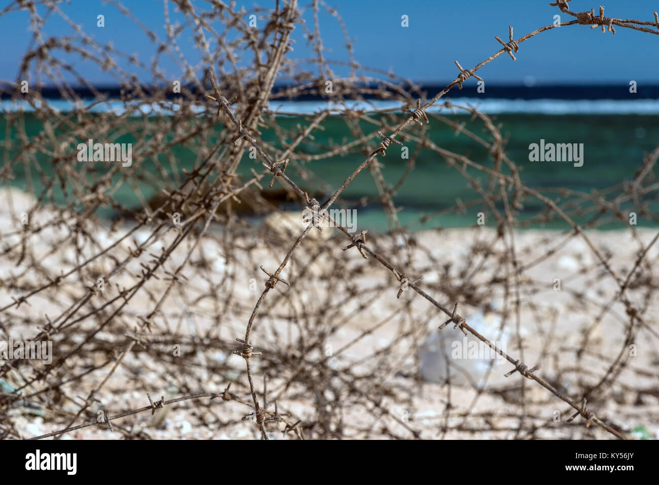 Old barbed wire infront of sea. Wire and blue sky with clouds. Safety ...