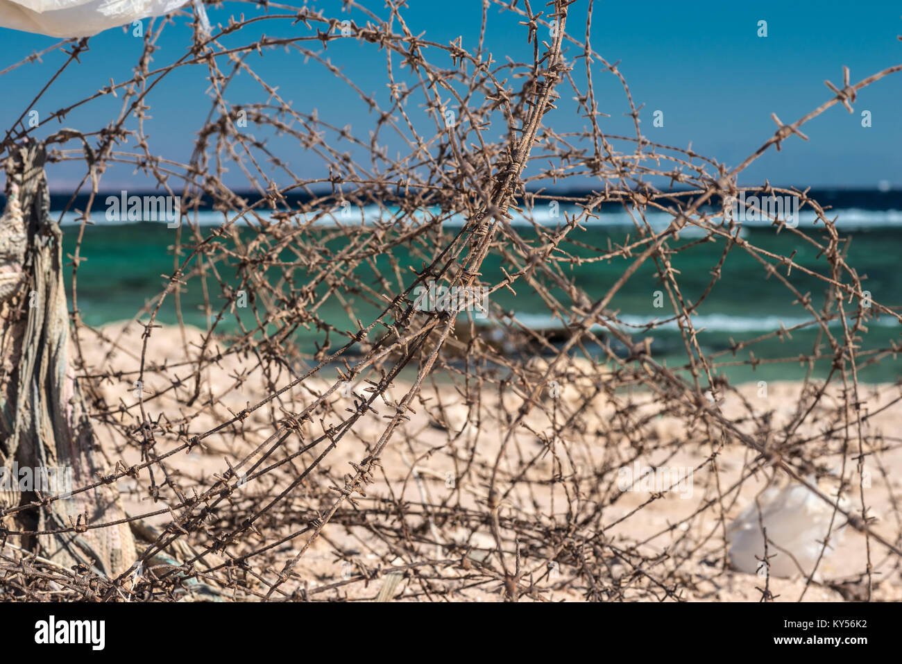 Old barbed wire infront of sea. Wire and blue sky with clouds. Safety ...
