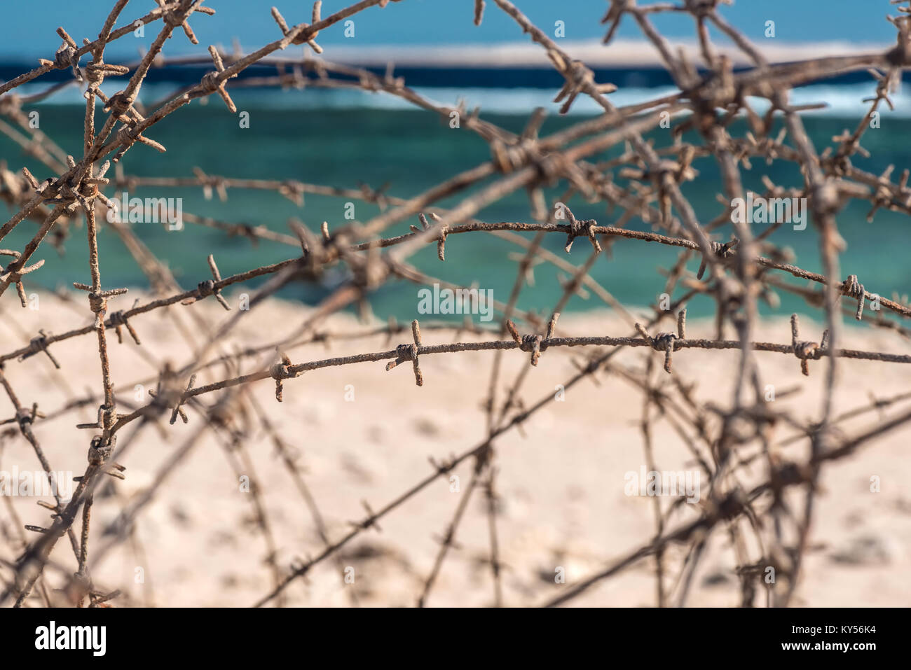 Old barbed wire infront of sea. Wire and blue sky with clouds. Safety ...