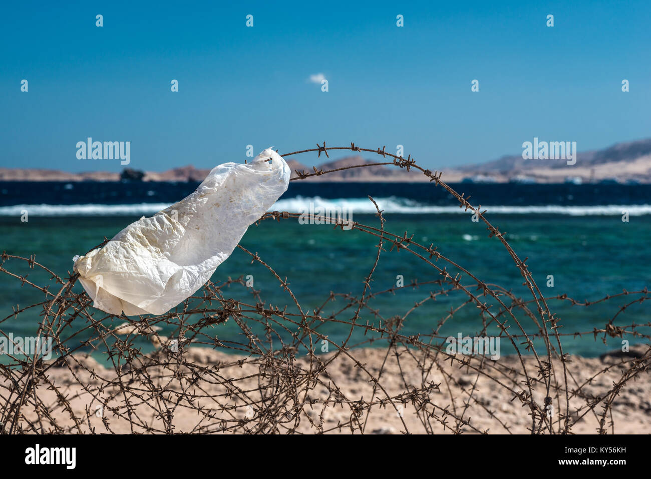 Old barbed wire infront of sea. Wire and blue sky with clouds. Safety ...