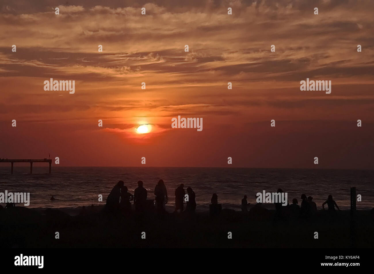 A beautiful California sunset with a wooden pier extending into the ...