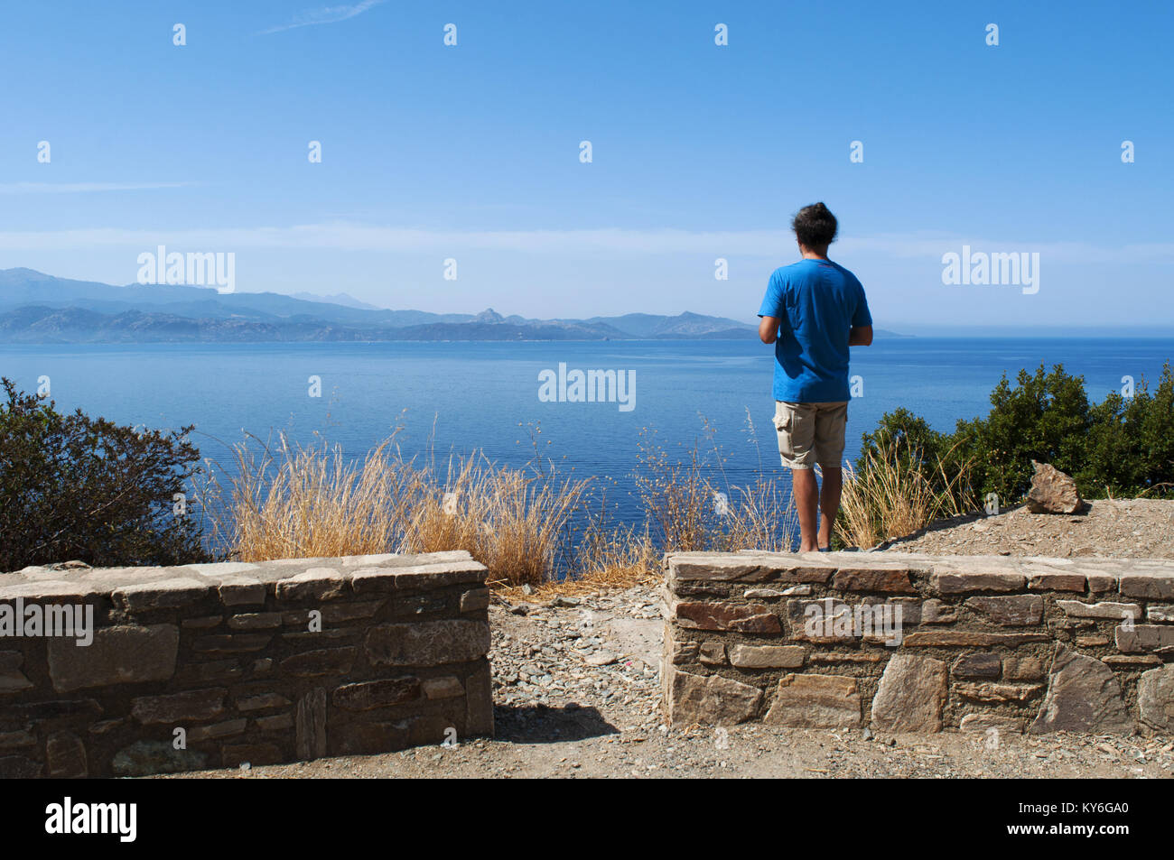 Corsica: a man looking the jagged and green coastline of the western ...