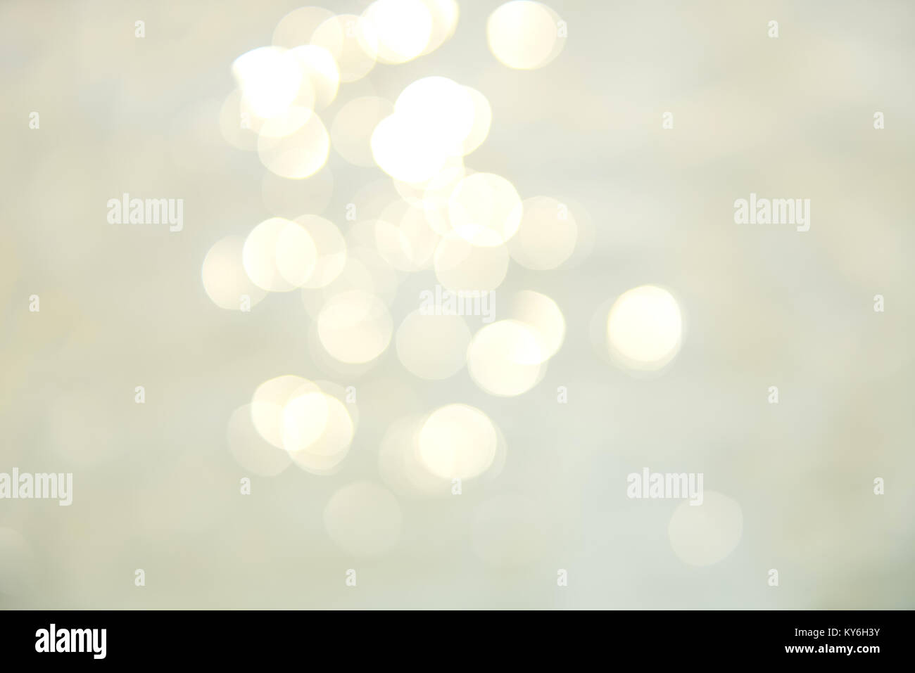 Soft focus bokeh light effects over a rippled, blue water background in ...