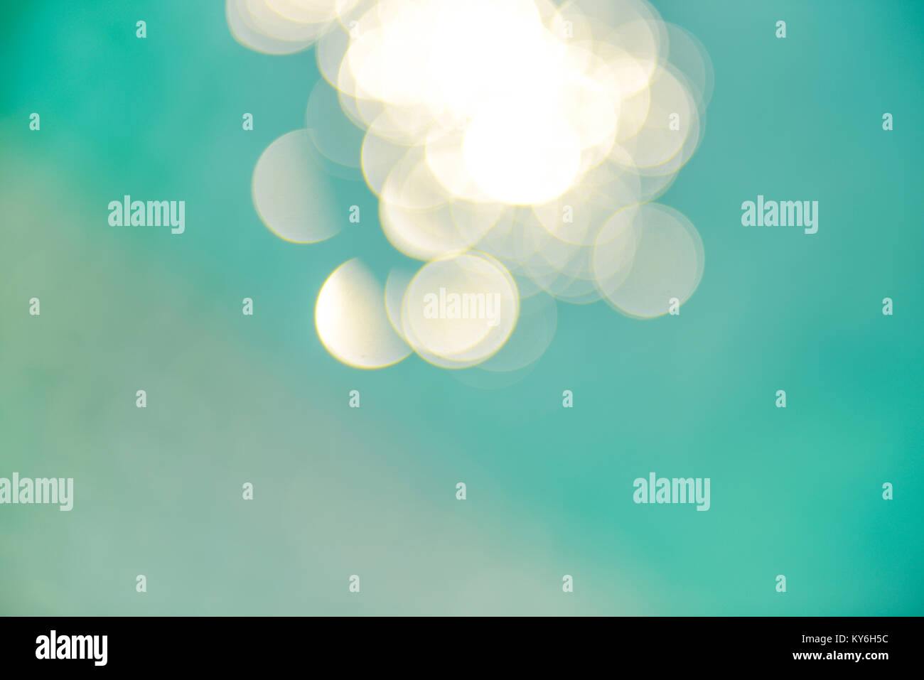 Soft focus bokeh light effects over a rippled, blue water background in ...