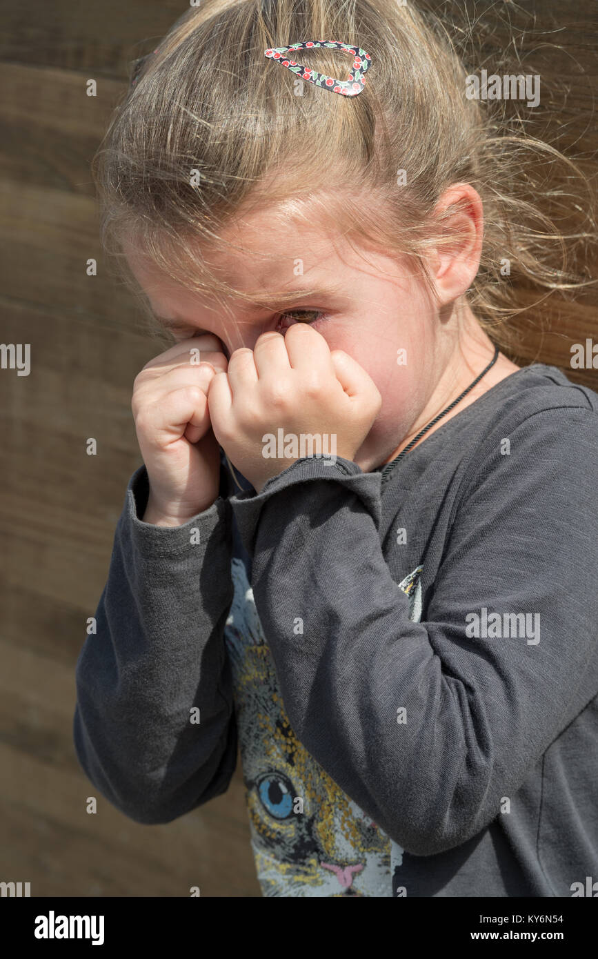 Little girl cry beside wooden wall Stock Photo - Alamy