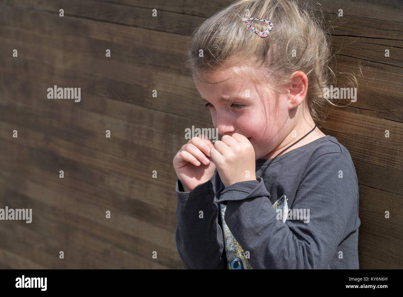 Little girl cry beside wooden wall Stock Photo - Alamy
