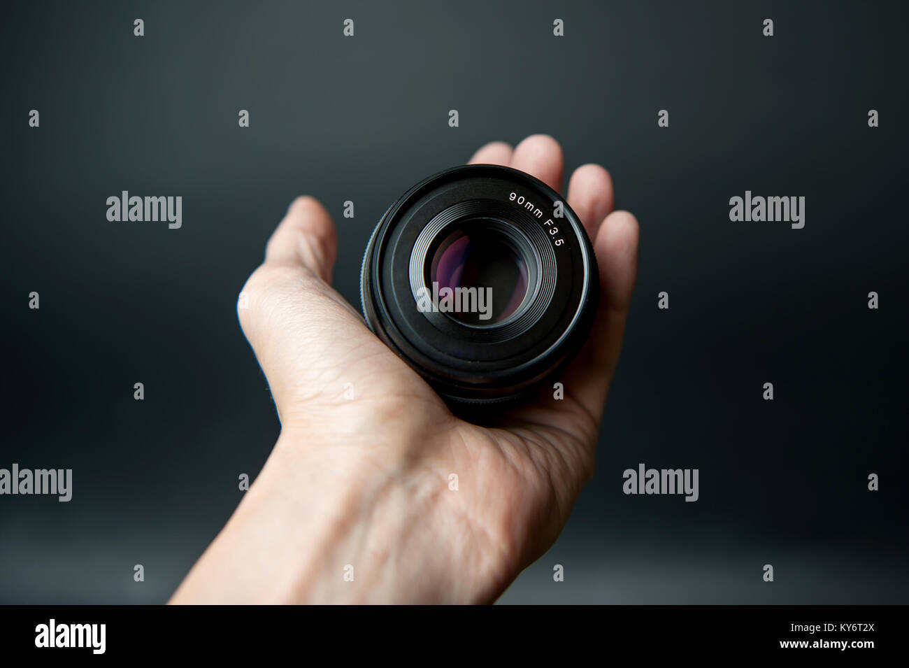 man's hand holding a camera lens on a black background Stock Photo - Alamy