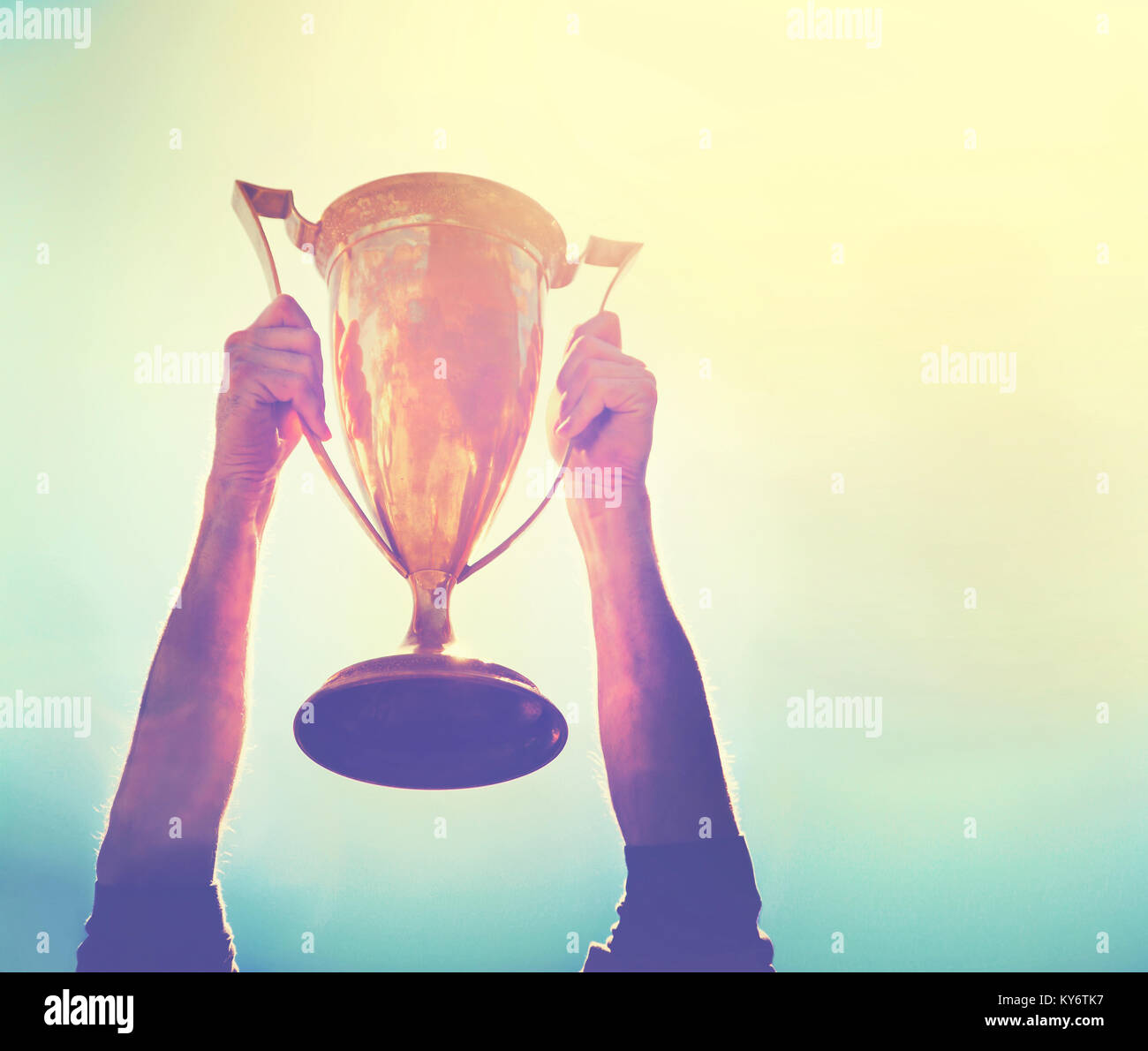a man holding up a gold trophy cup as a winner in a competition toned ...