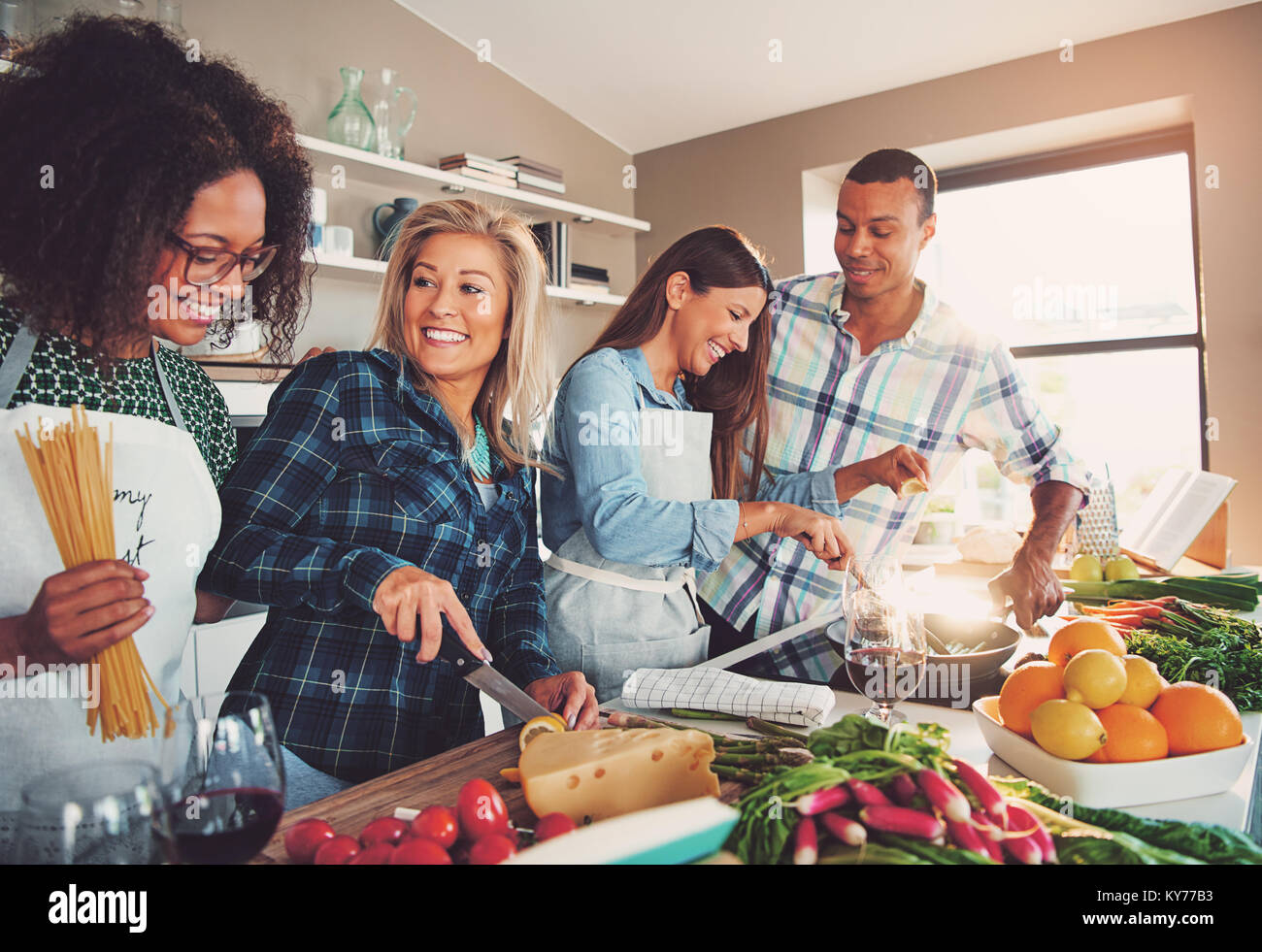 Portrait of four friends cheerfully cooking dinner at kitchen Stock ...