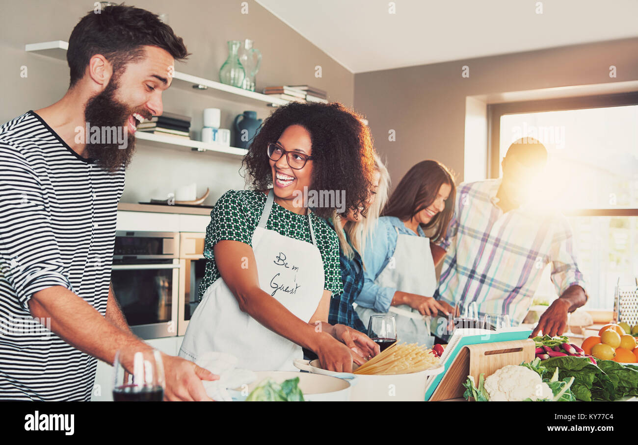 Laughing group of young cooking students in kitchen with bright ...