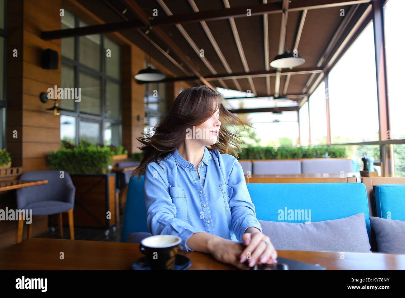 Beautiful lady enjoying windy weather at cafe . Pretty girl sitting on ...