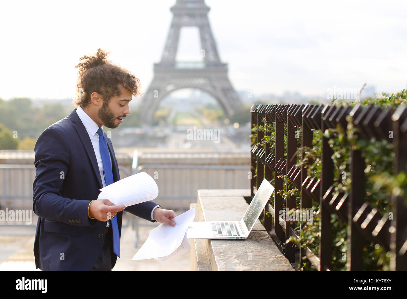 Mulatto man using laptop on open air around Eiffel Tower in slow motion ...