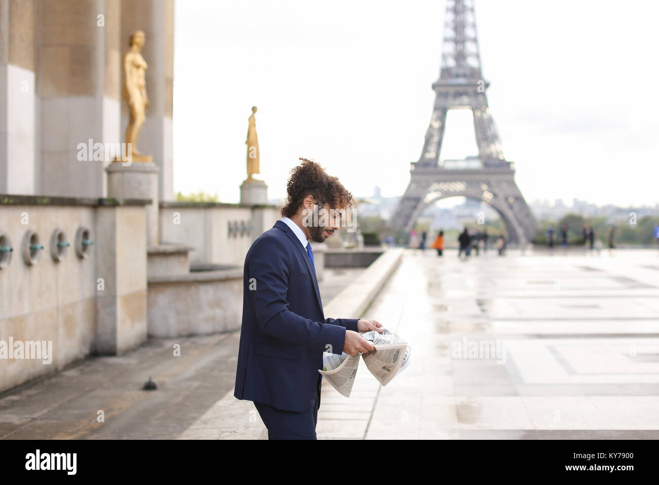 Handsome smiling journalist reading French public press close to Eiffel ...