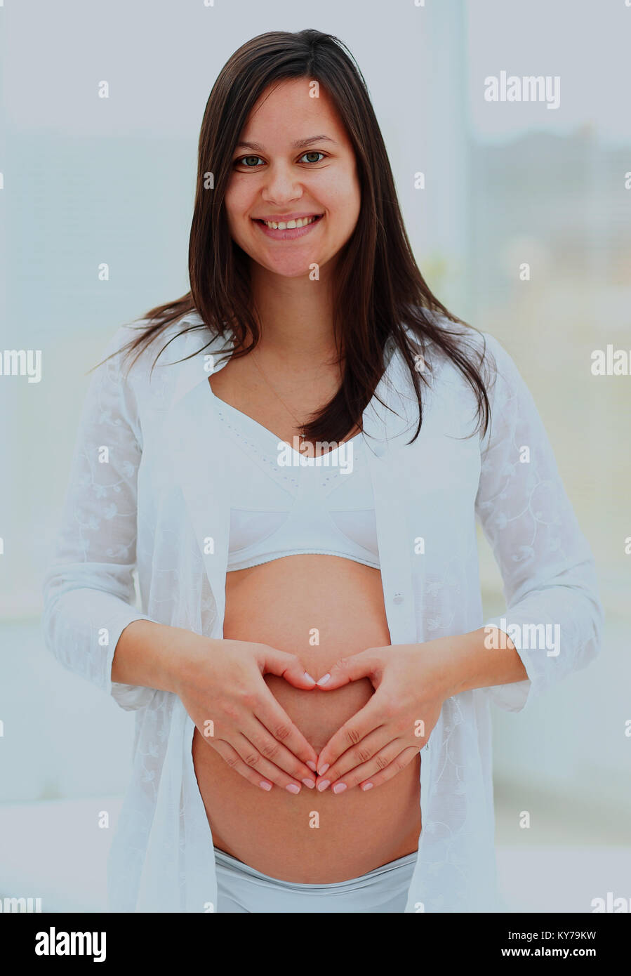 Pregnant woman shows the heart on her baby bump by hands Stock Photo ...