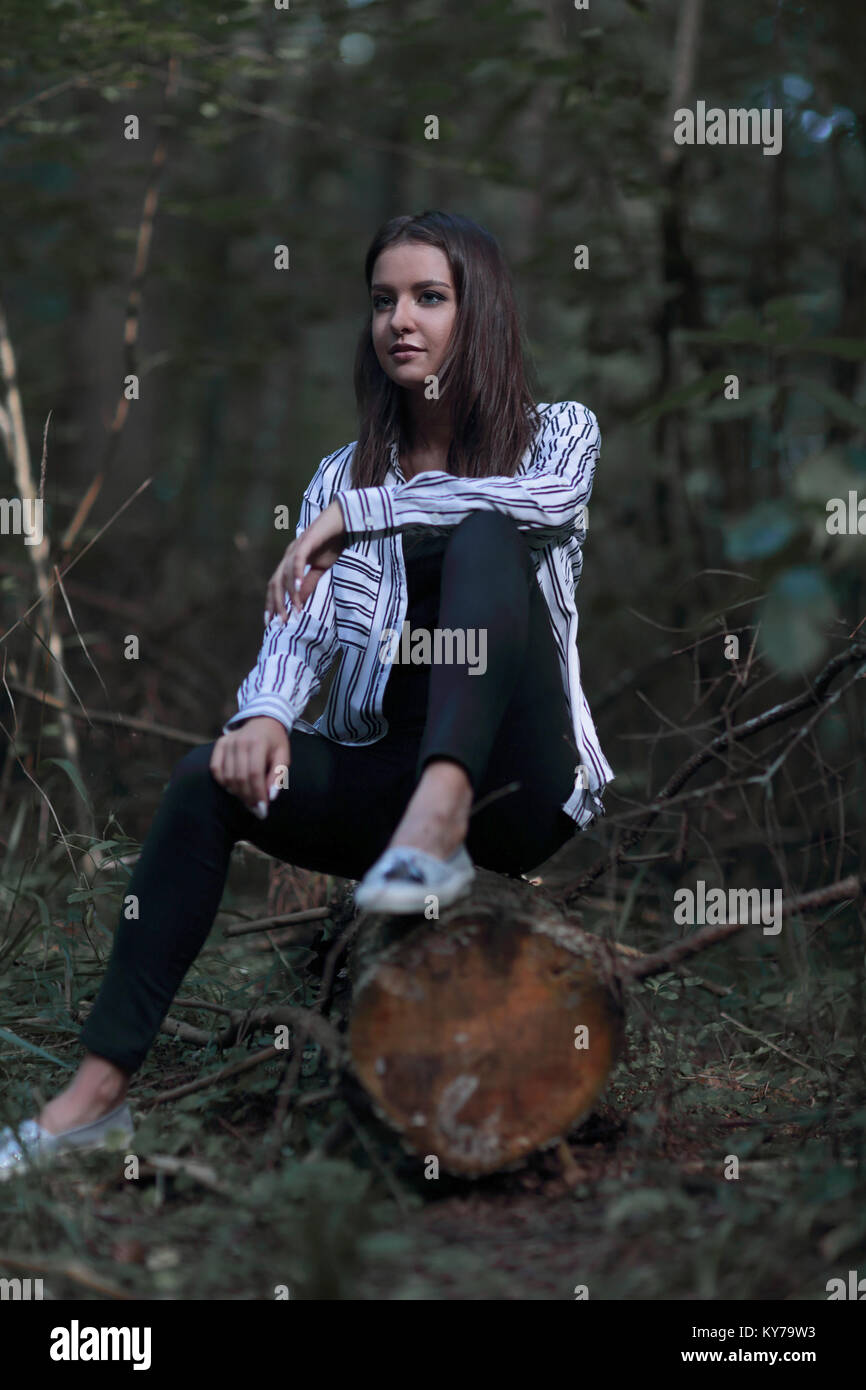 beautiful young woman sitting on a log Stock Photo - Alamy