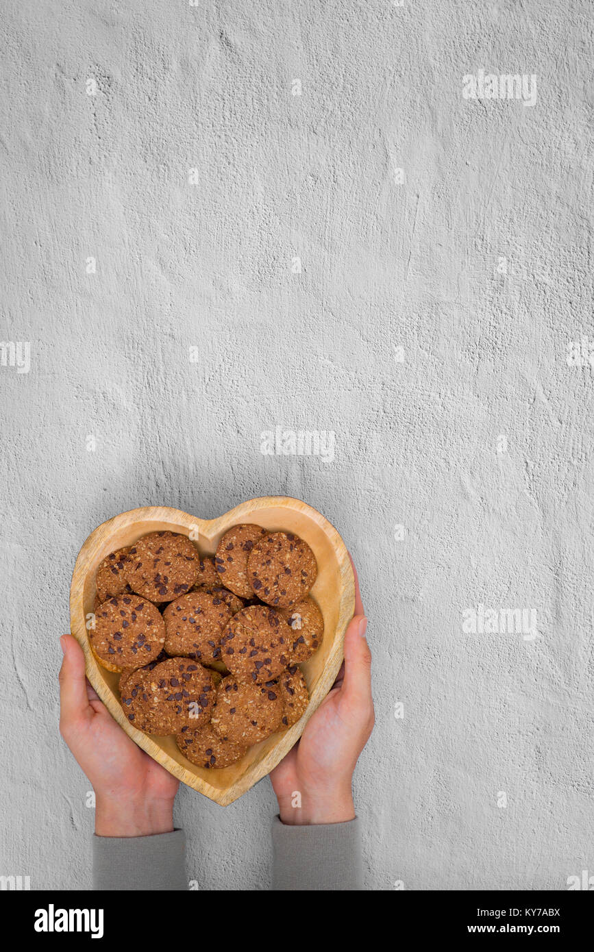 Hands holding heart shape plate with traditional chocolate chip cookies ...