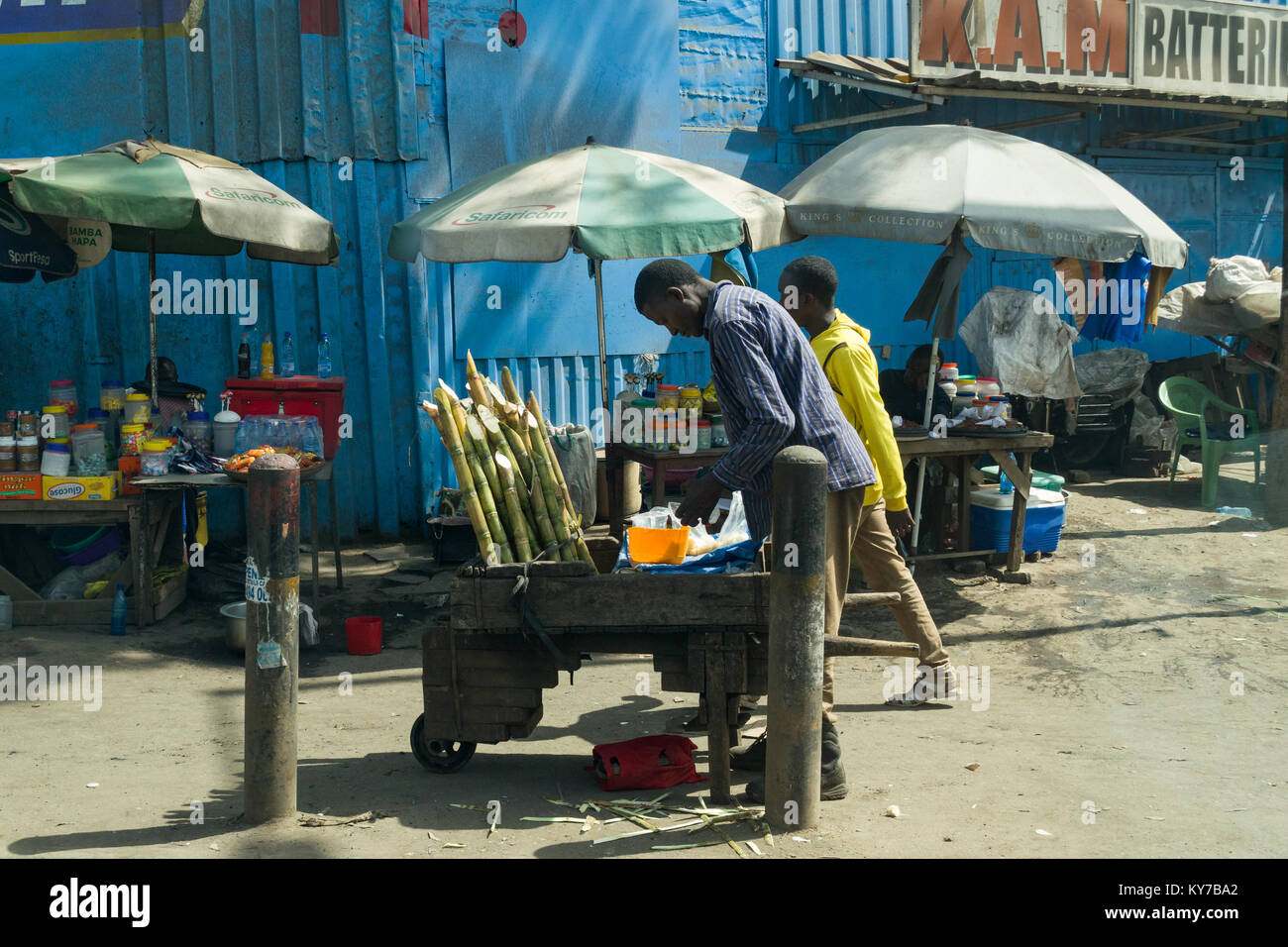 A man stands by his roadside stall preparing sugar cane for sale ...
