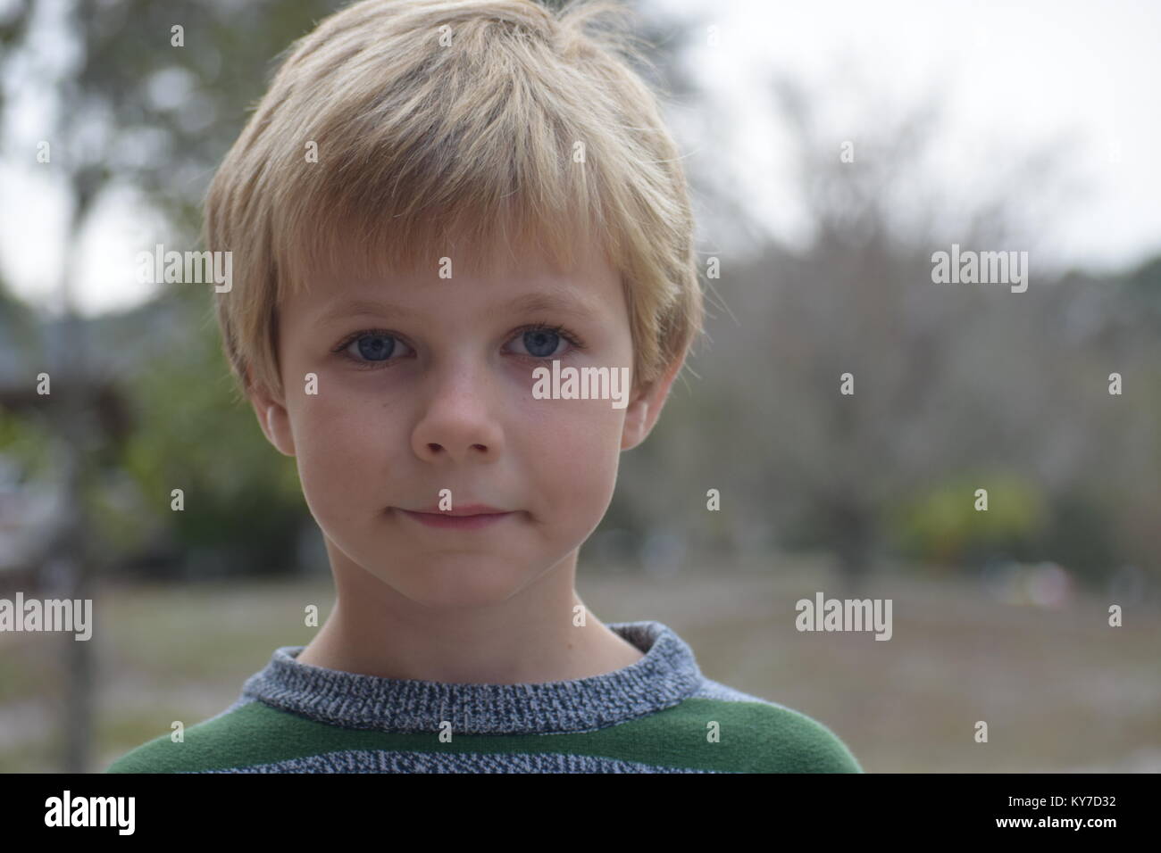 Blonde boy holding back a smile Stock Photo - Alamy