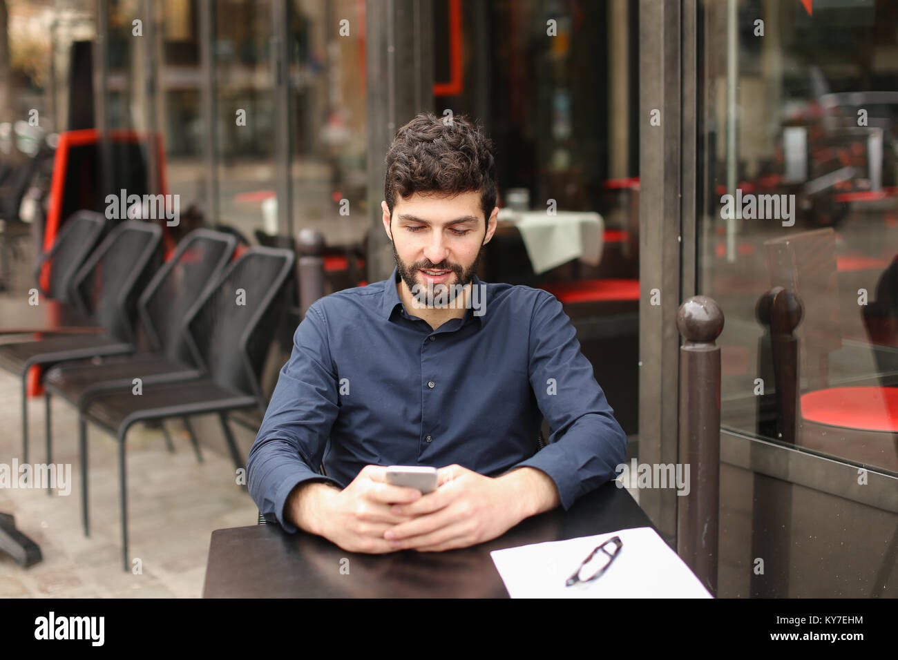 Happy man sitting at cafe table and chatting by smartphone with Stock ...