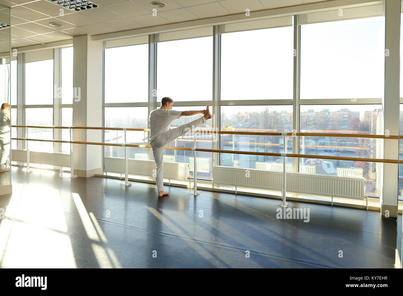 Young person making leg stretching near window Stock Photo - Alamy