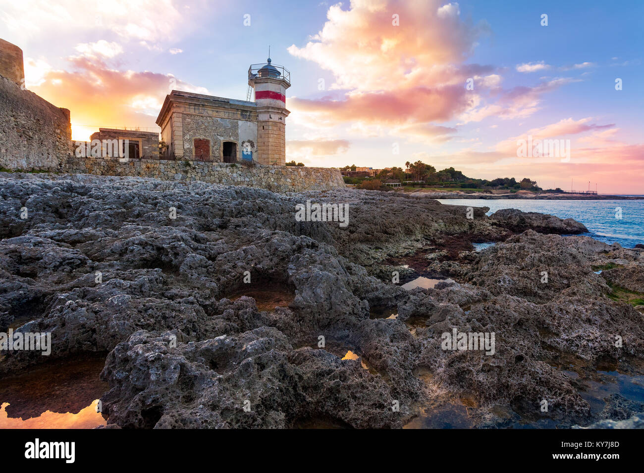 The castle of Brucoli and the little lighthouse reflected in a puddle ...