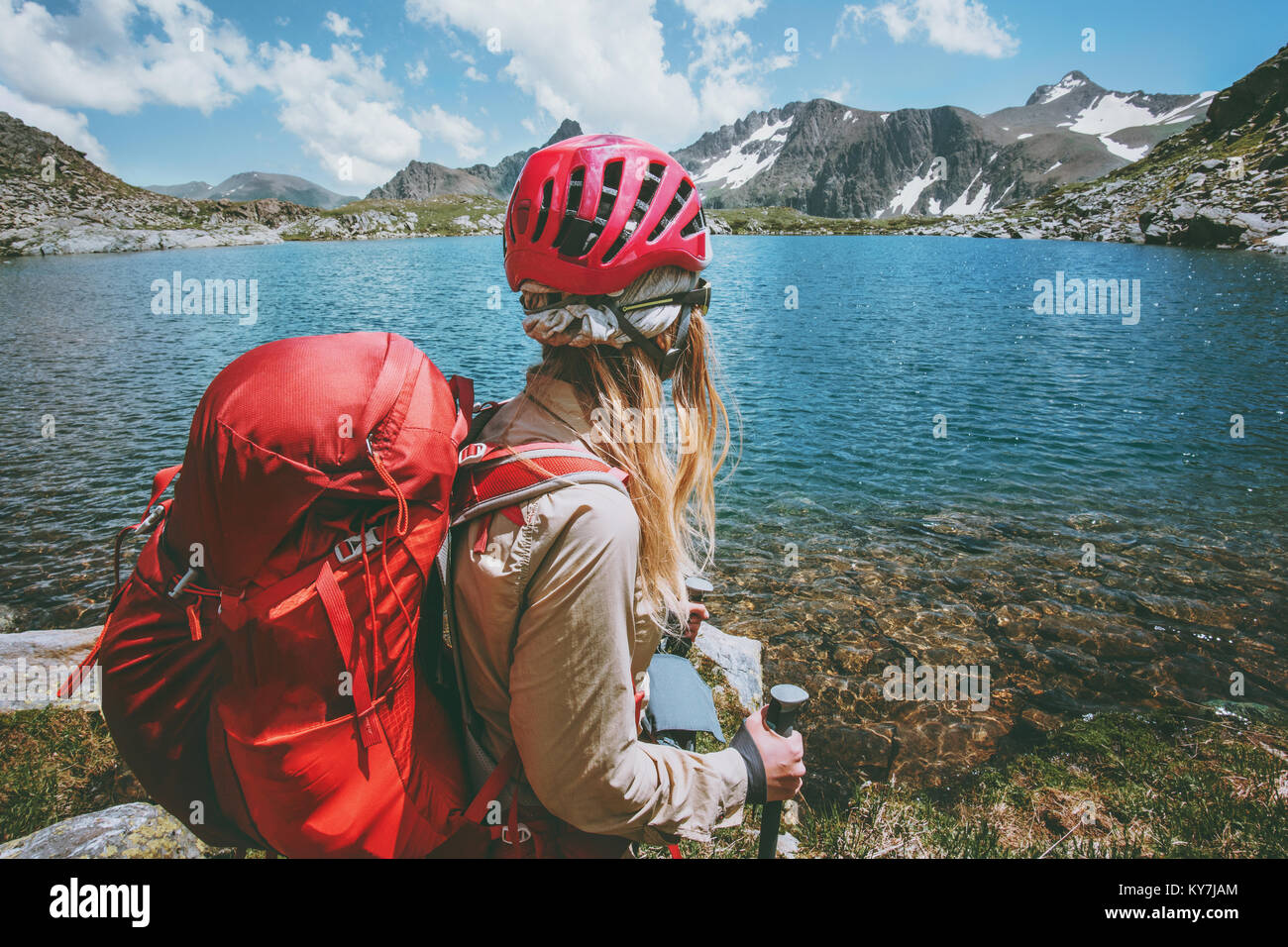 Backpacker girl hiking at blue lake in mountains with red backpack ...