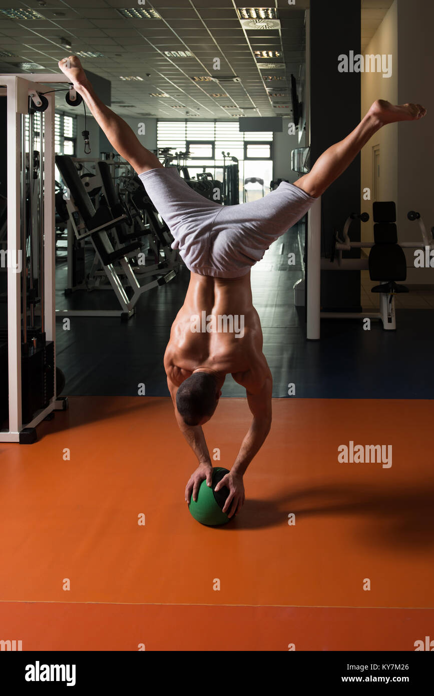 Athlete Doing Handstand Push-Ups On Medicine Ball As Part Of ...