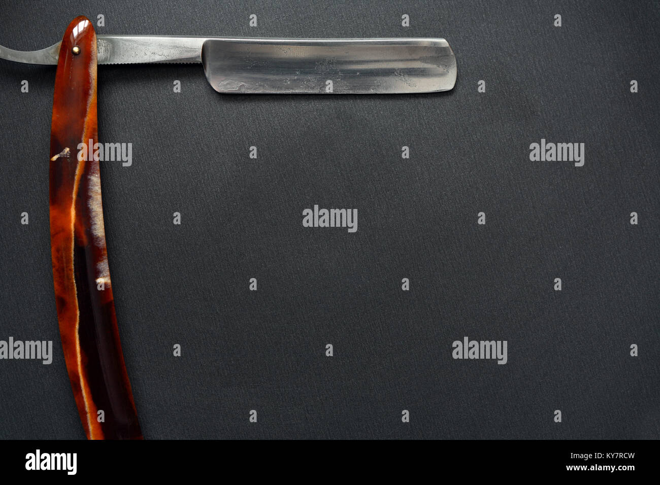 Very old rusty classic straight razor lying on dark metal background ...