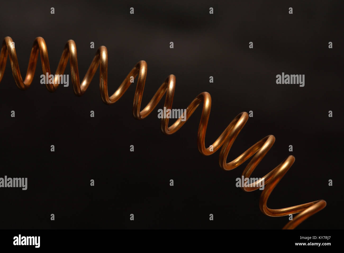 Closeup of brass spring isolated on dark background Stock Photo - Alamy