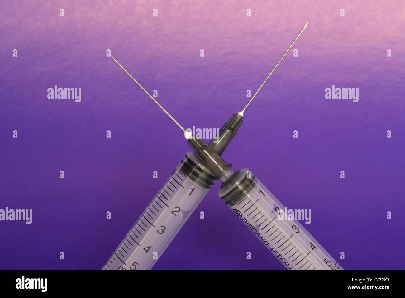 A simple plastic syringes with hypodermic needles on abstract purple ...