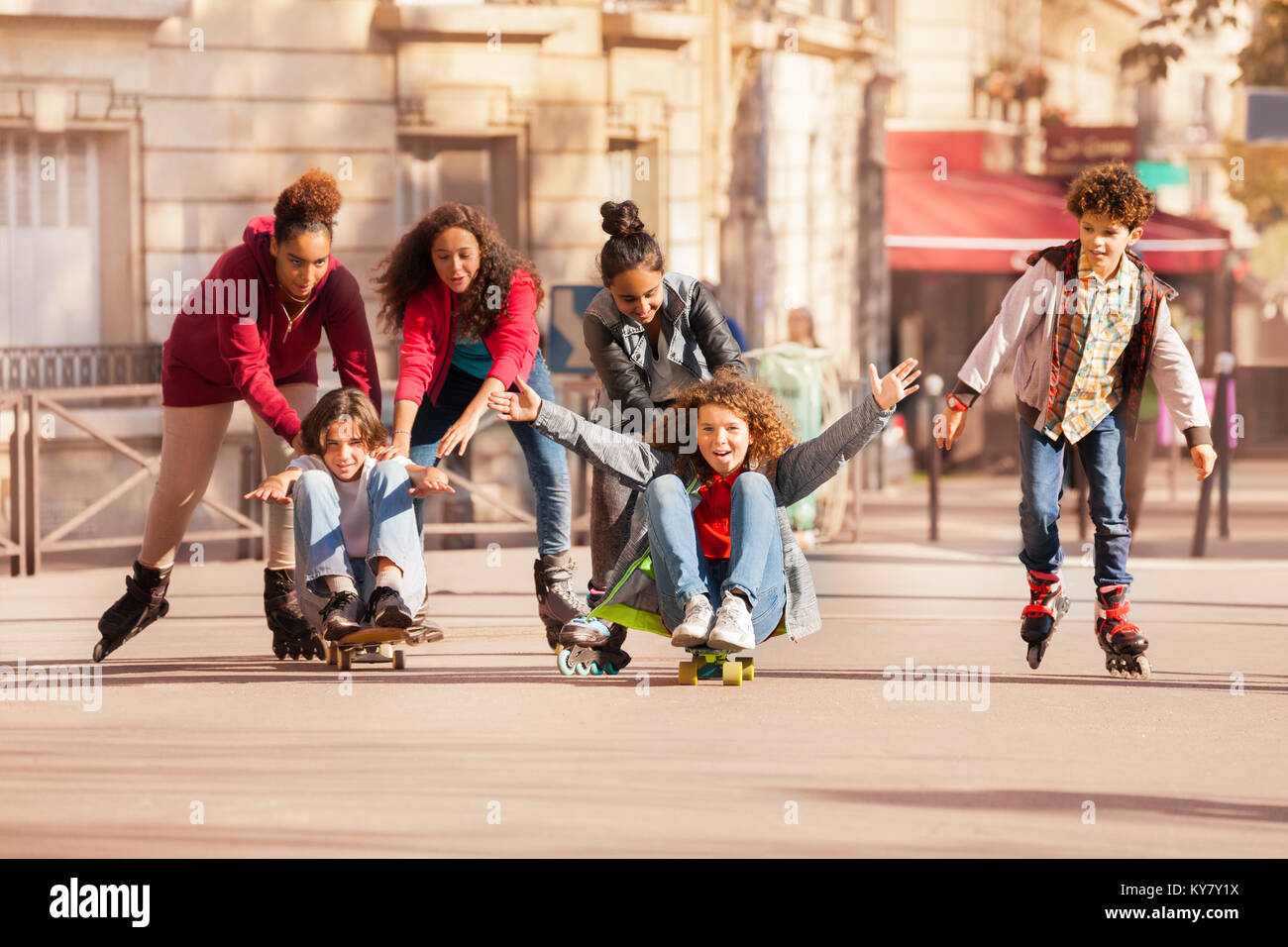 Group of happy teenagers having fun rollerblading and skateboarding ...