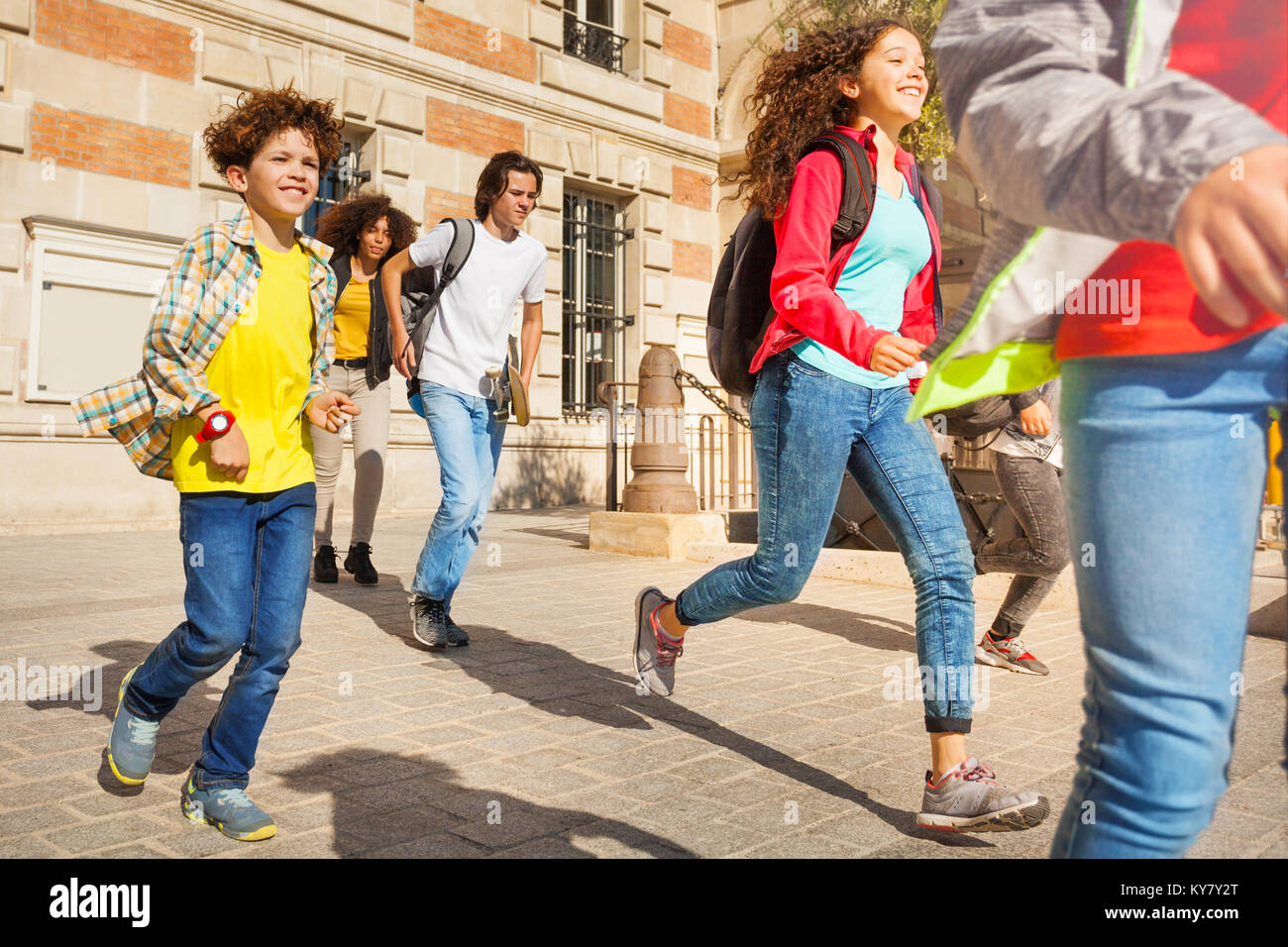 Group of mixed race teenage boys and girls, running after the classes ...