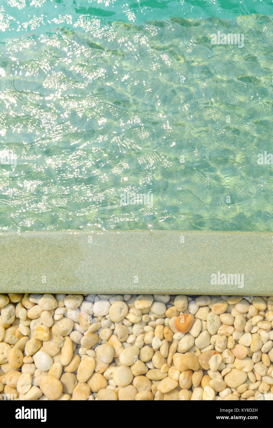 Closeup of stone border in front of bright blue swimming pool ...
