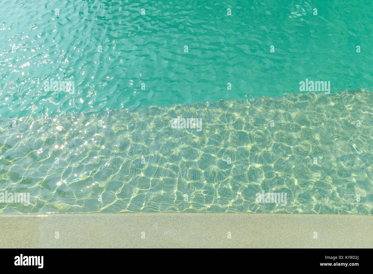 Closeup of stone border in front of bright blue swimming pool ...