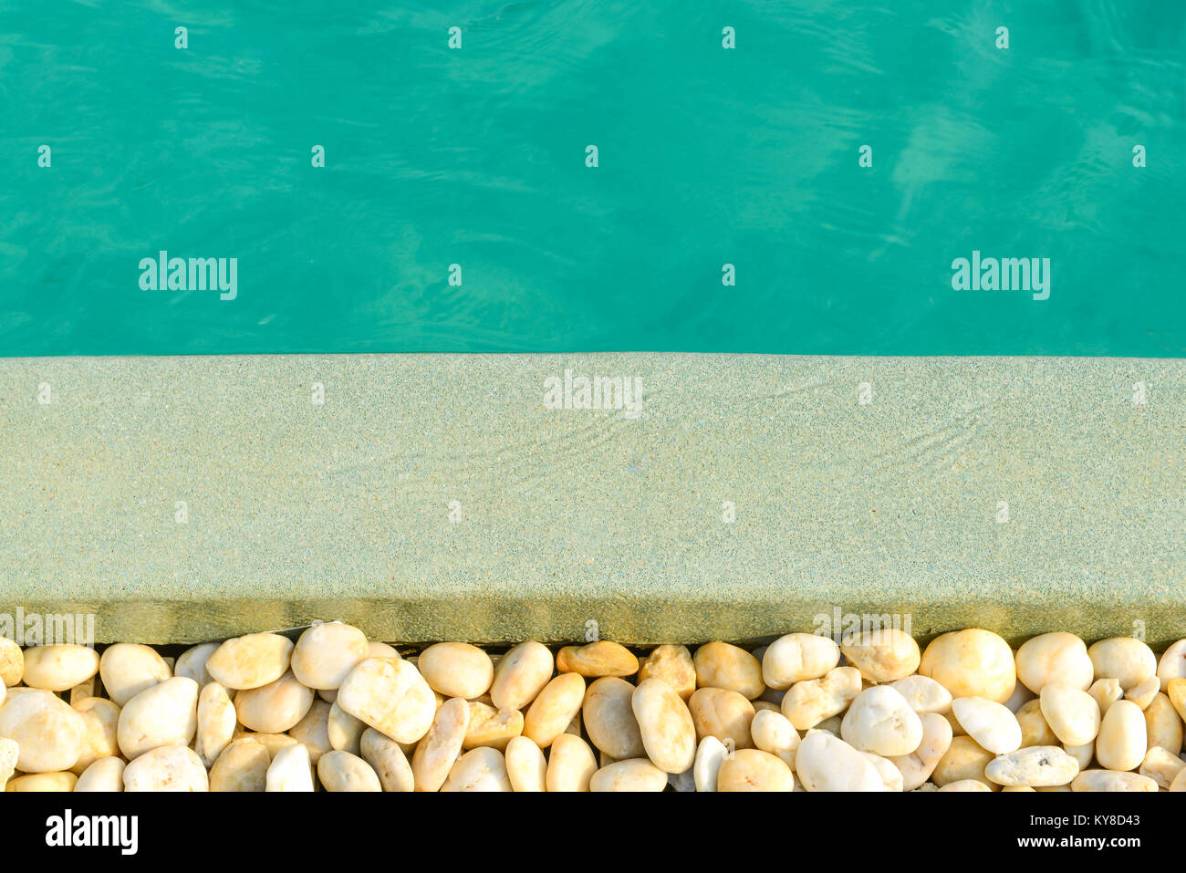 Closeup of stone border in front of bright blue swimming pool ...
