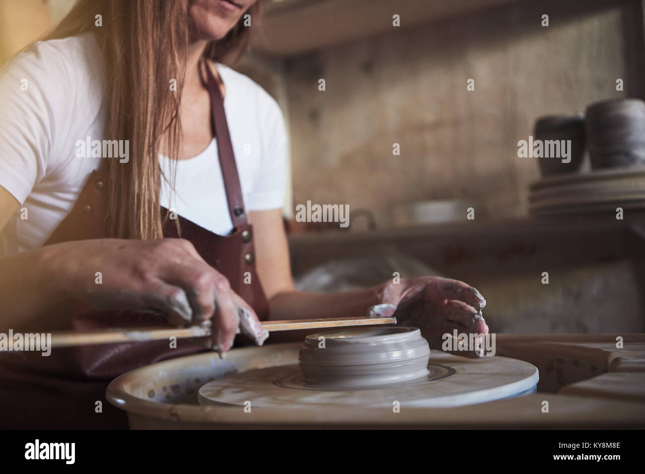 Artisan sitting in her creative ceramic workshop using a ruler to ...