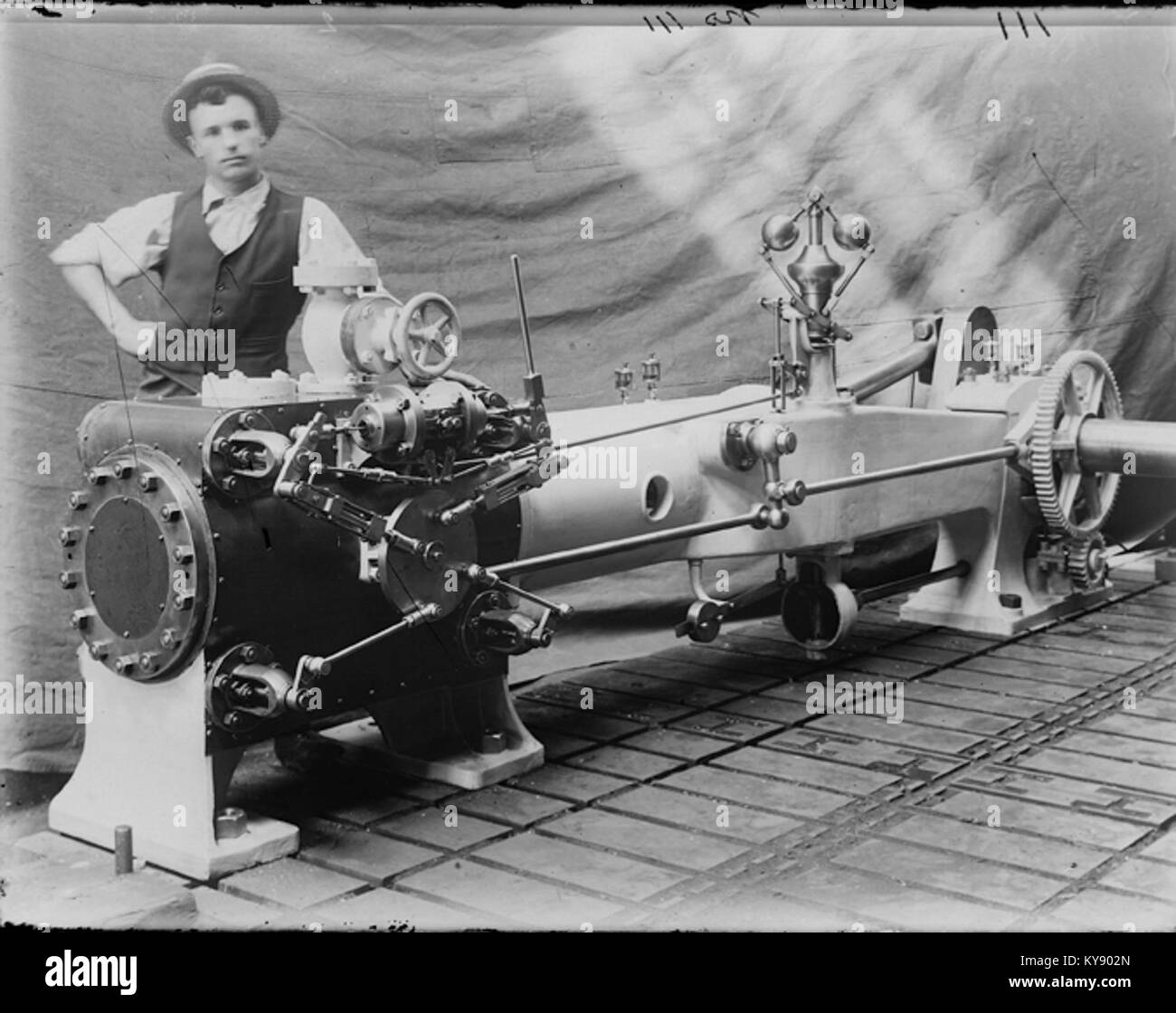 A photograph of a worker operating a horizontal Corliss steam engine ...