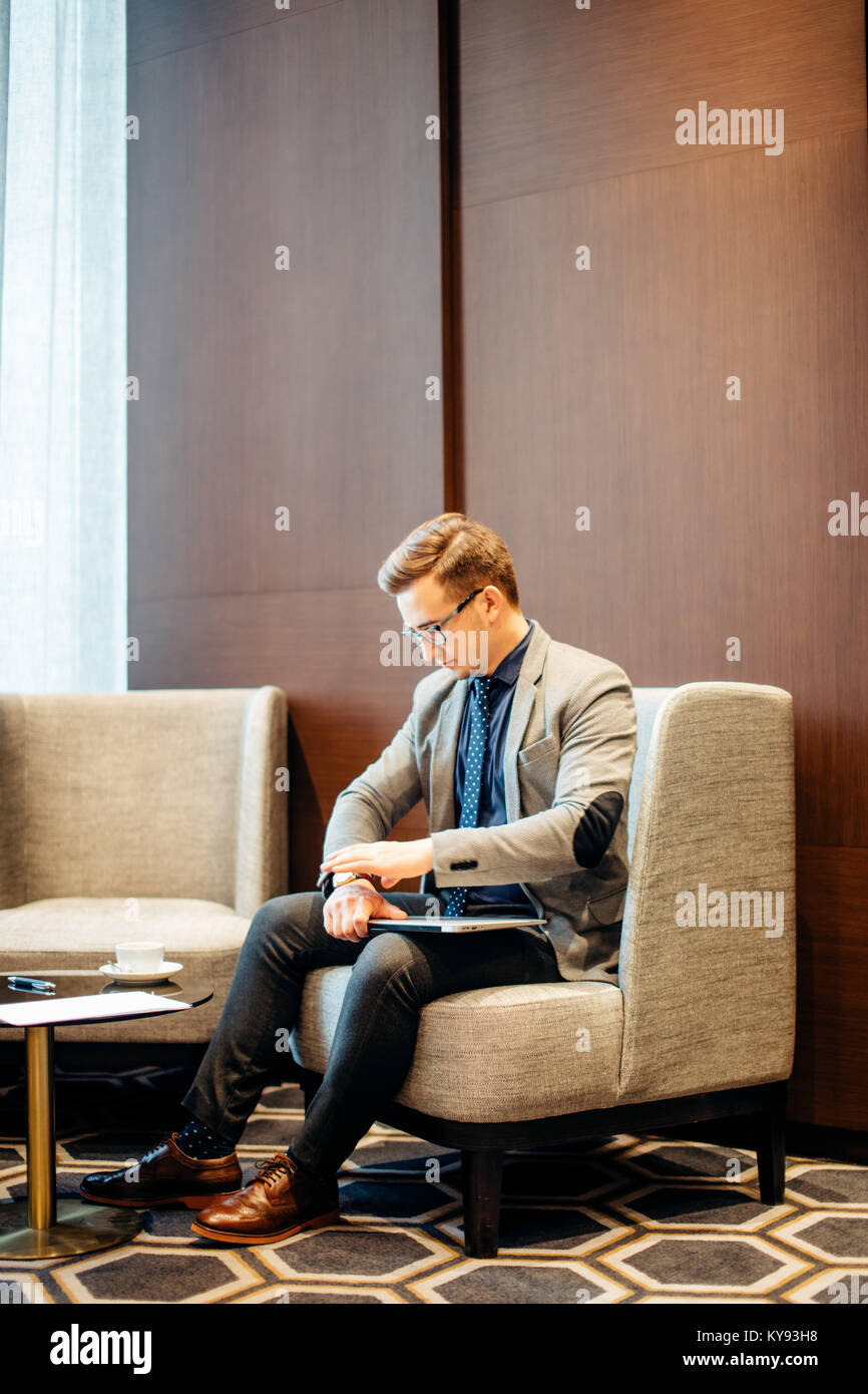 man is preparing for interview. He in suit, sitting in hall on chair ...