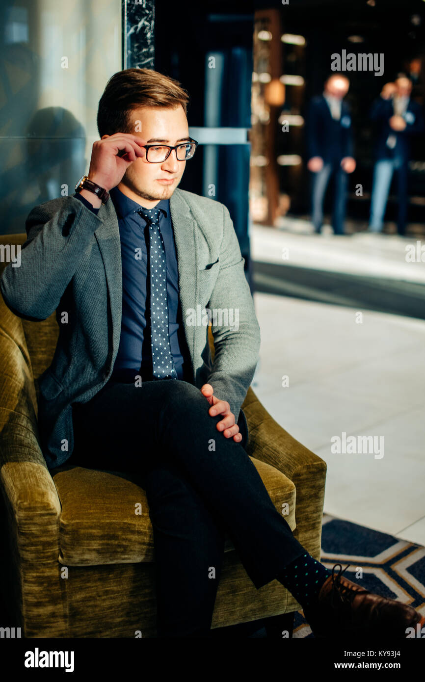 man is preparing for interview. He in suit, sitting in hall on chair ...