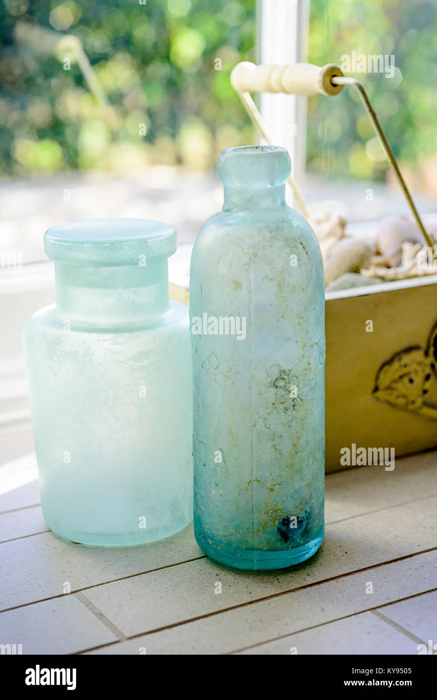 Antique blue bottles on counter in bathroom with soft window light ...
