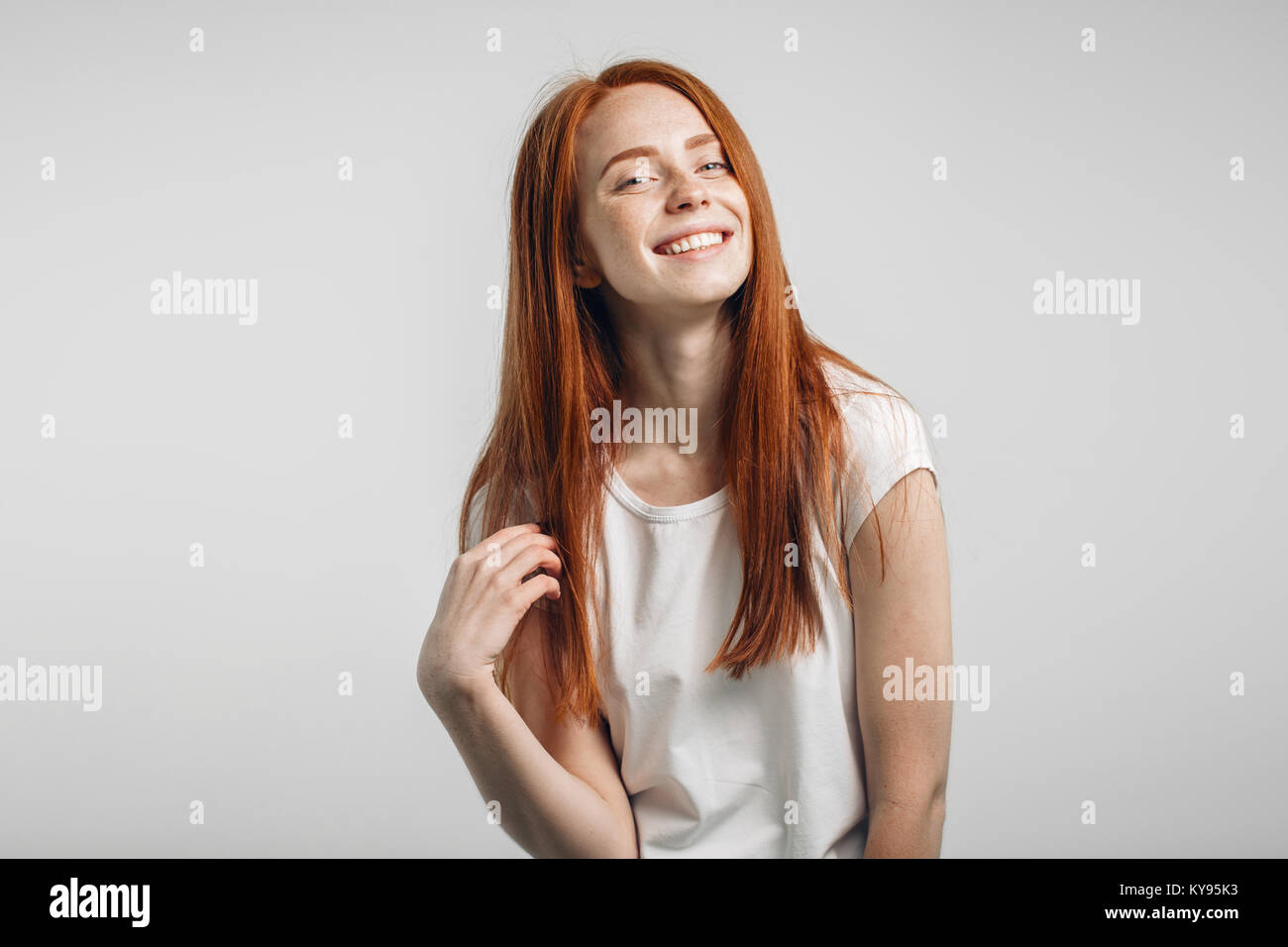 girl smiling with closed eyes touching her red hair over white background Stock Photo - Alamy