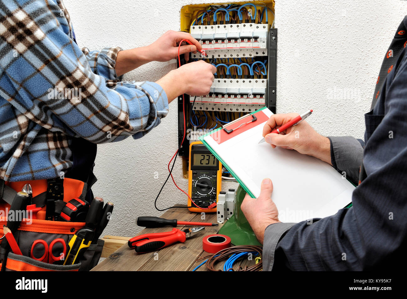 The engineer writes on a notepad the measurement of the voltage of the ...