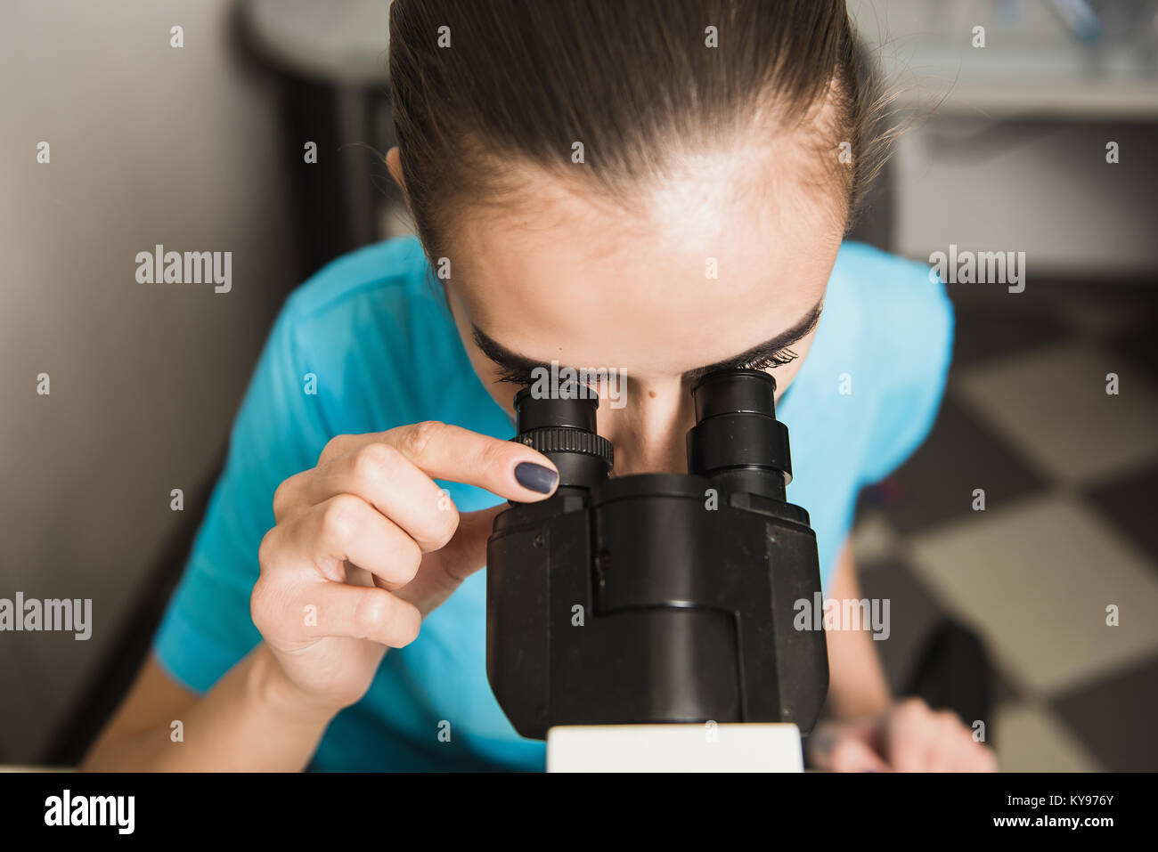 Attractive scientist looking through a microscope in a lab. View from ...