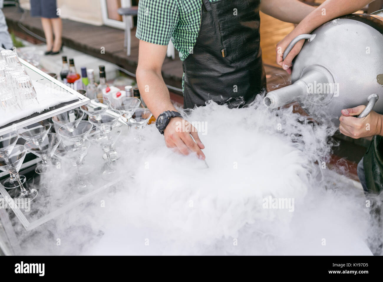 bartenders serve the cocktail in a large bowl with liquid nitrogen. row ...
