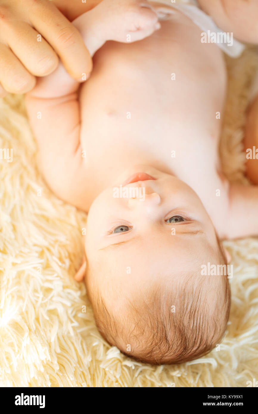 newborn baby lying down smiling looking at camera while father holding his head Stock Photo - Alamy